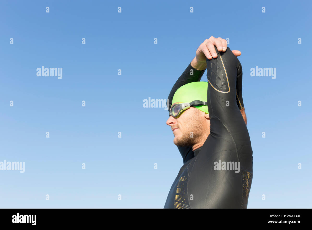 Triathlete preparing to swim, stretching arms and shoulders Stock Photo ...