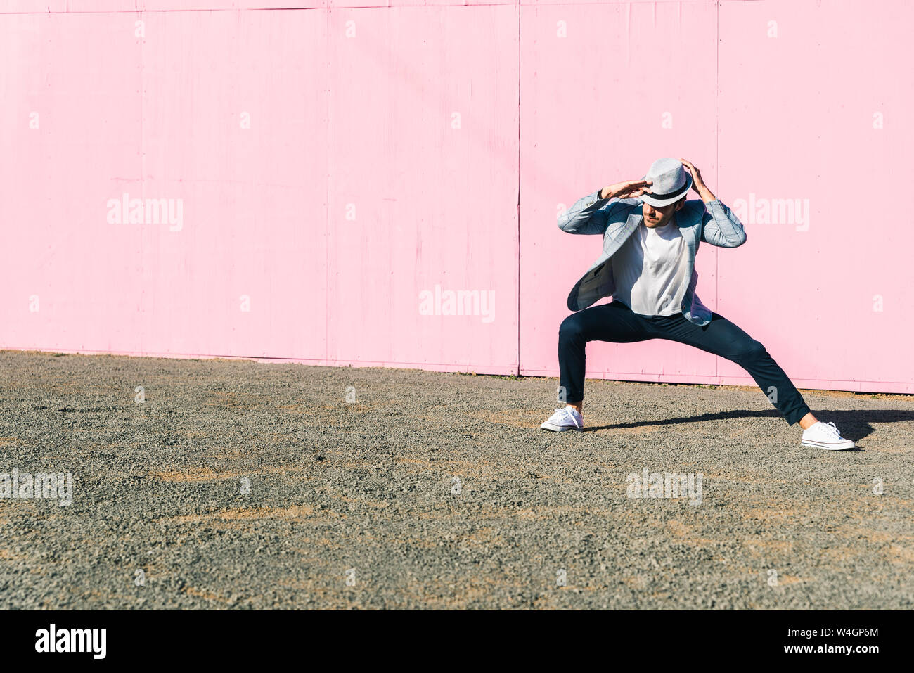 Young man in front of pink construction barrier, crouching, holding his ...