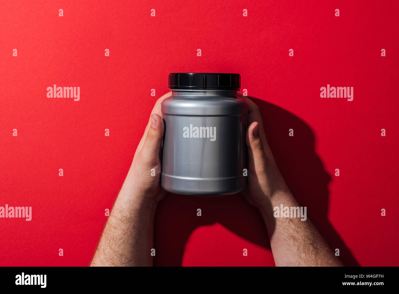 cropped view of man holding grey jar in hands on red Stock Photo - Alamy