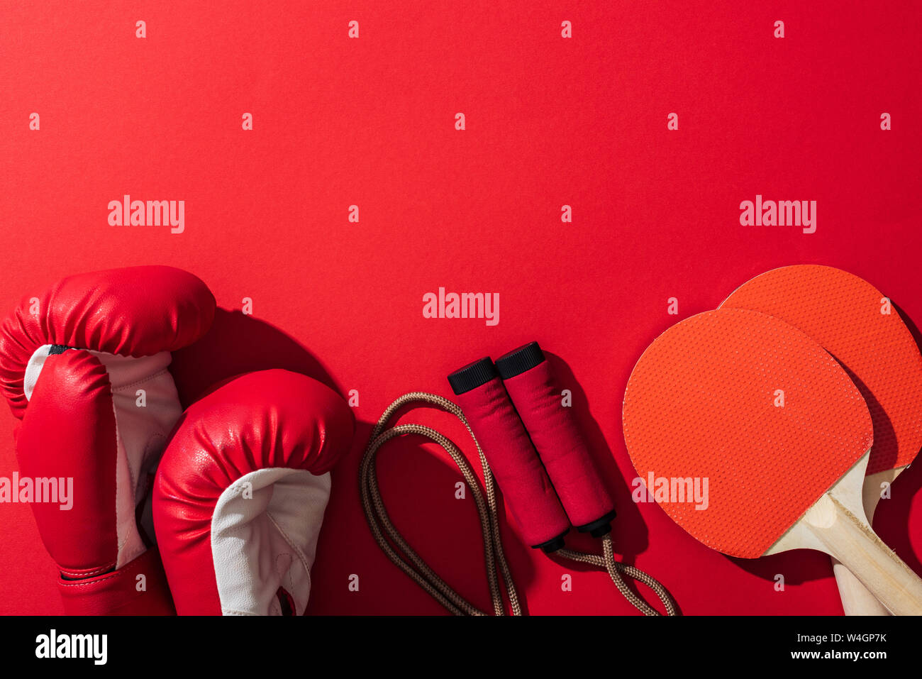 top view of boxing gloves near red ping pong rackets and skipping rope ...