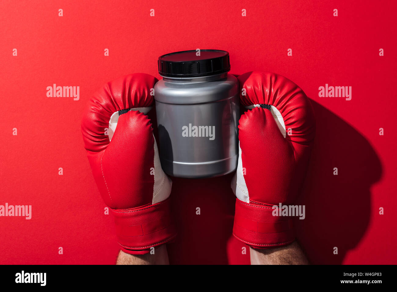 cropped view of man holding grey jar in boxing gloves on red Stock ...