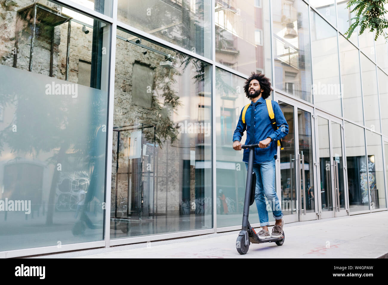 Man with backpack riding fast with his E-Scooter on pavement Stock ...