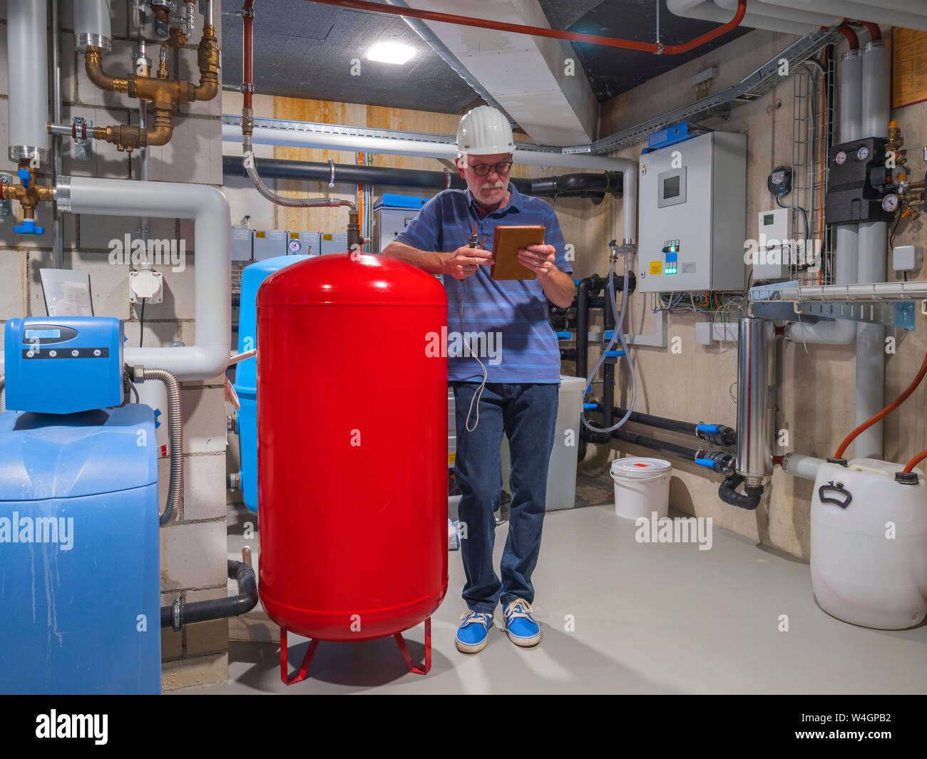 Senior craftsman checking water-processing unit, reading tablet Stock ...