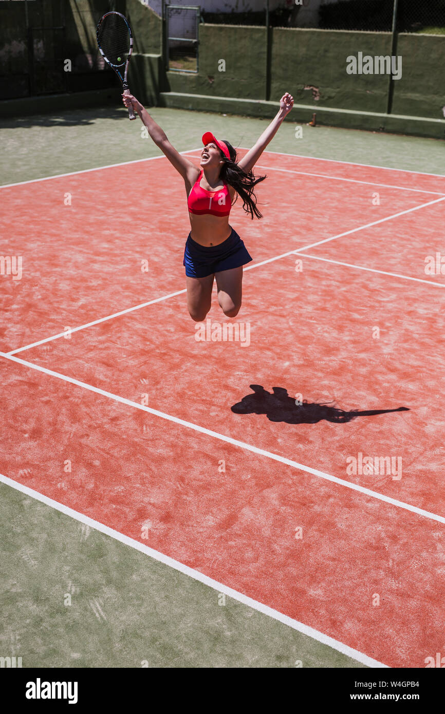 Excited female tennis player cheering on court Stock Photo - Alamy