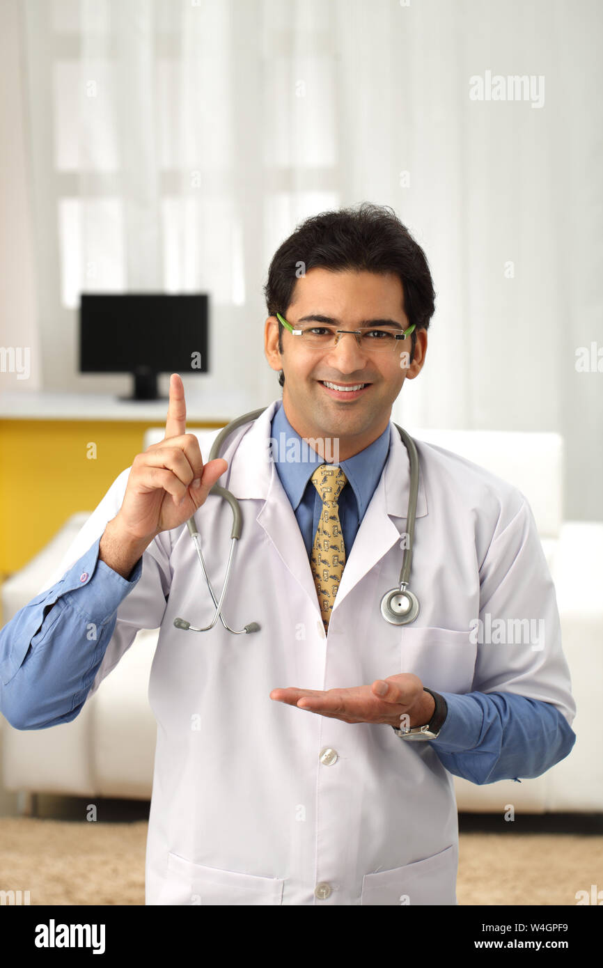 Male doctor pointing upward and smiling Stock Photo - Alamy