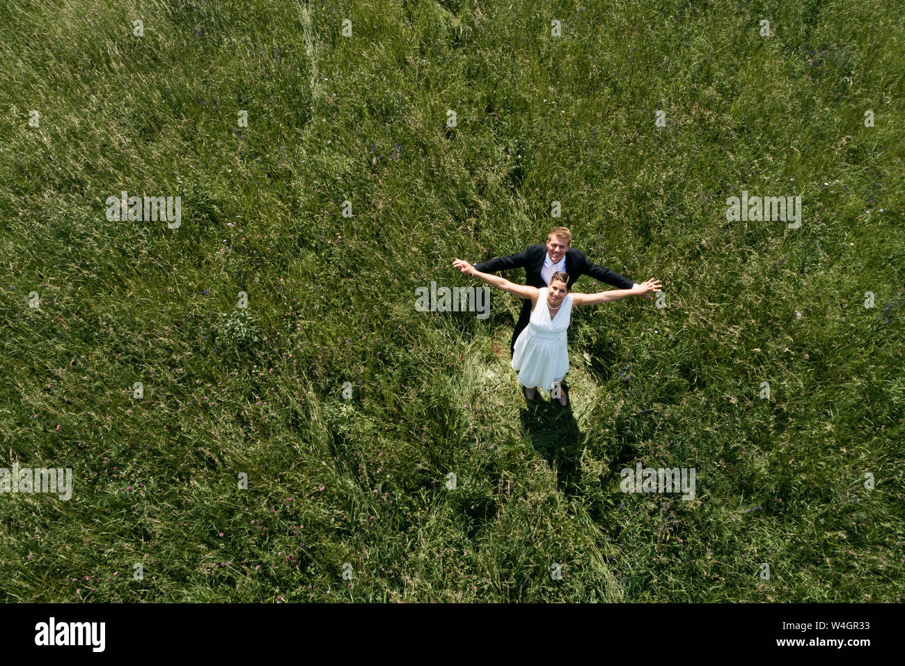 Aerial view of pregnant bride with her husband on a meadow Stock Photo ...