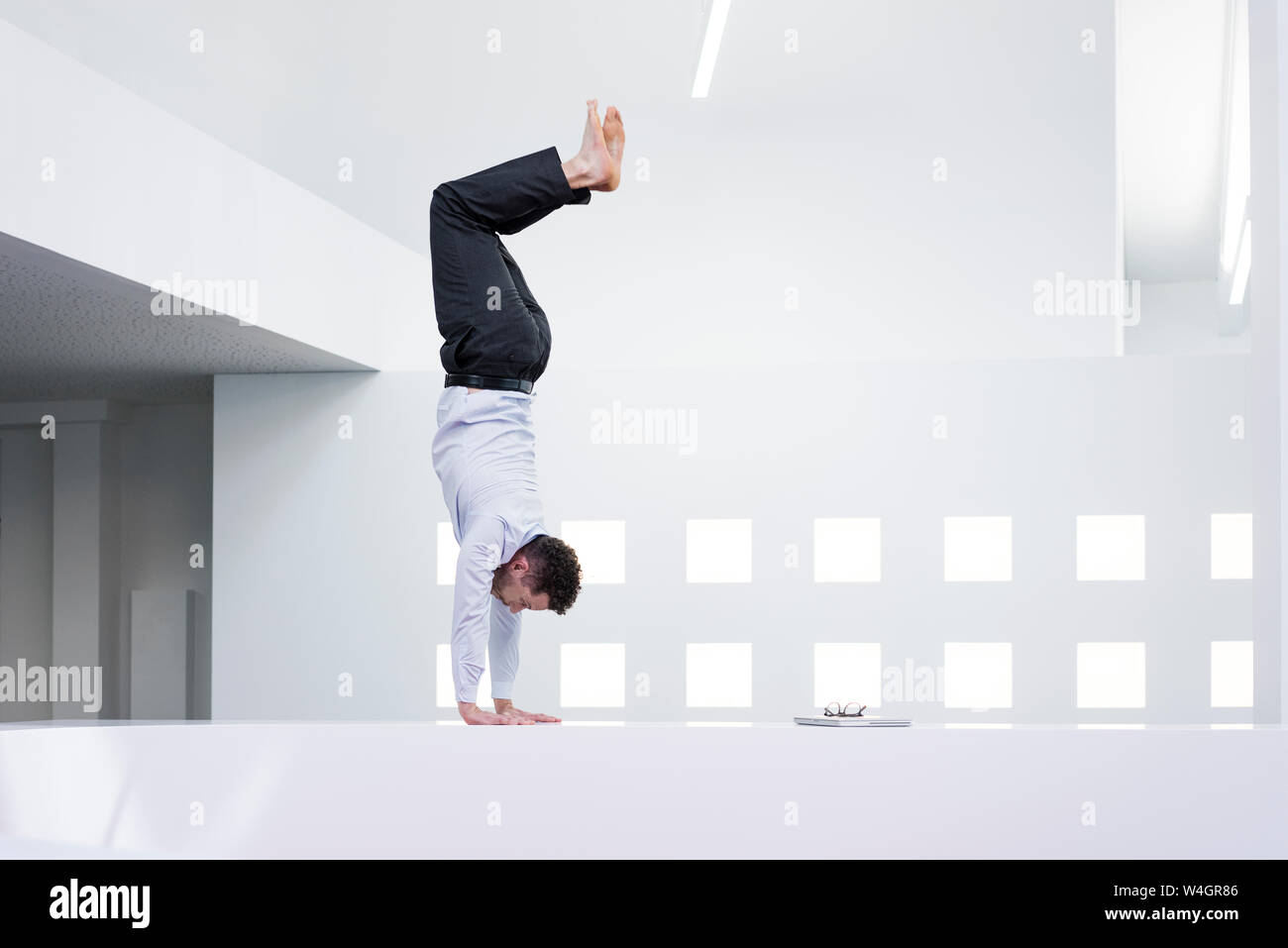 Businessman doing a handstand on reception desk in office Stock Photo ...