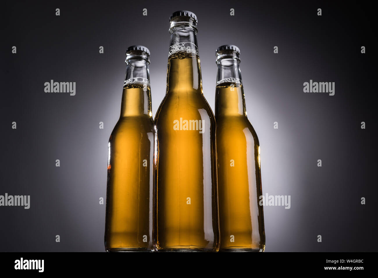 low angle view of glass bottles with beer on dark background with back ...