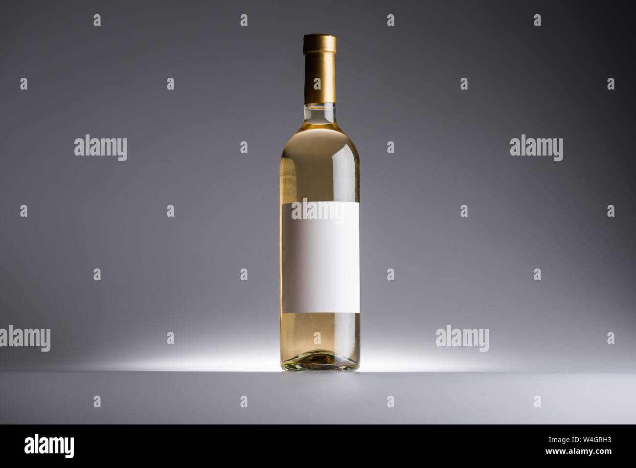bottle of white wine and blank label on dark background with back light ...