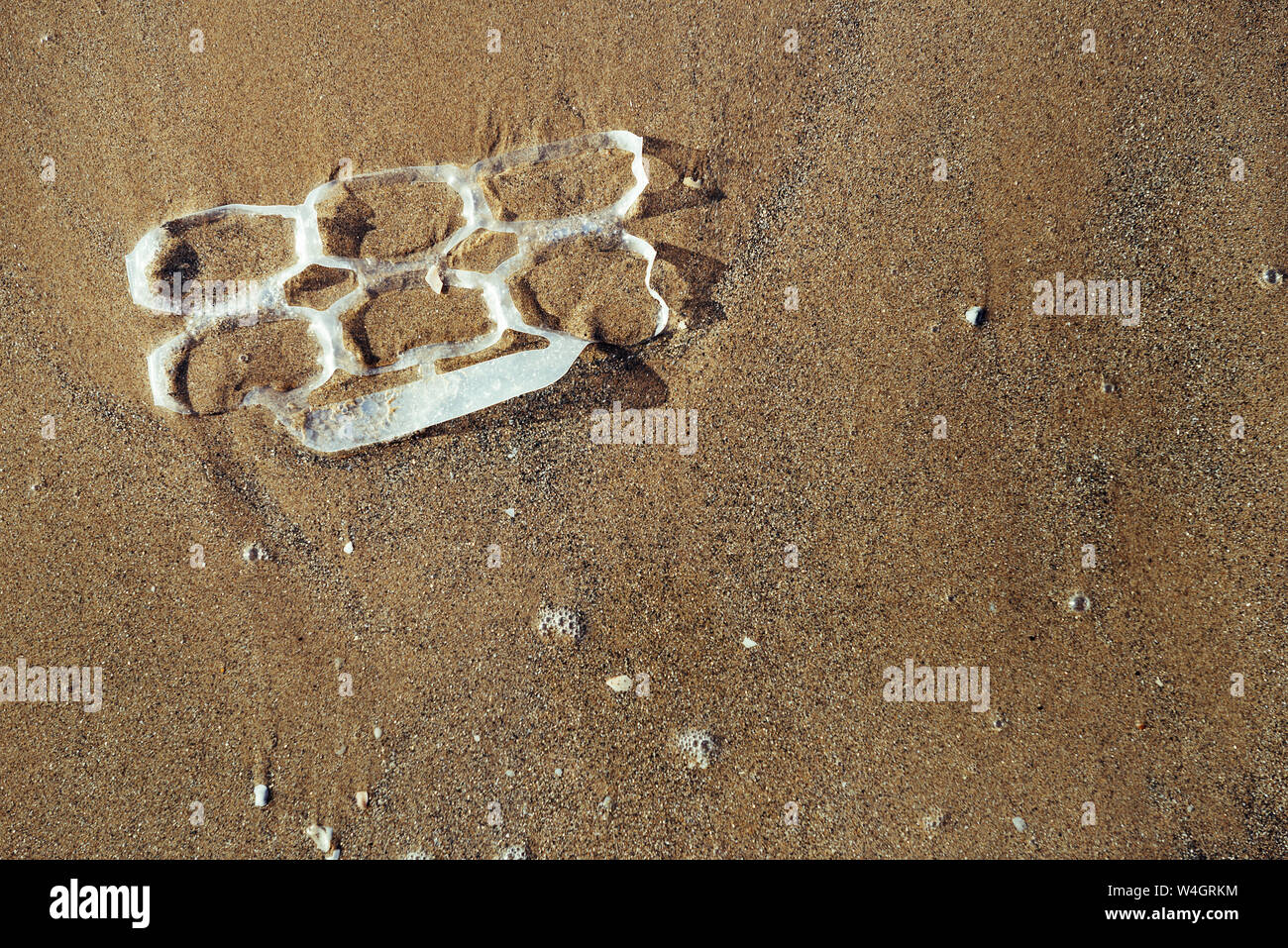 background of a plastic rings lying on the sand of the beach polluting ...