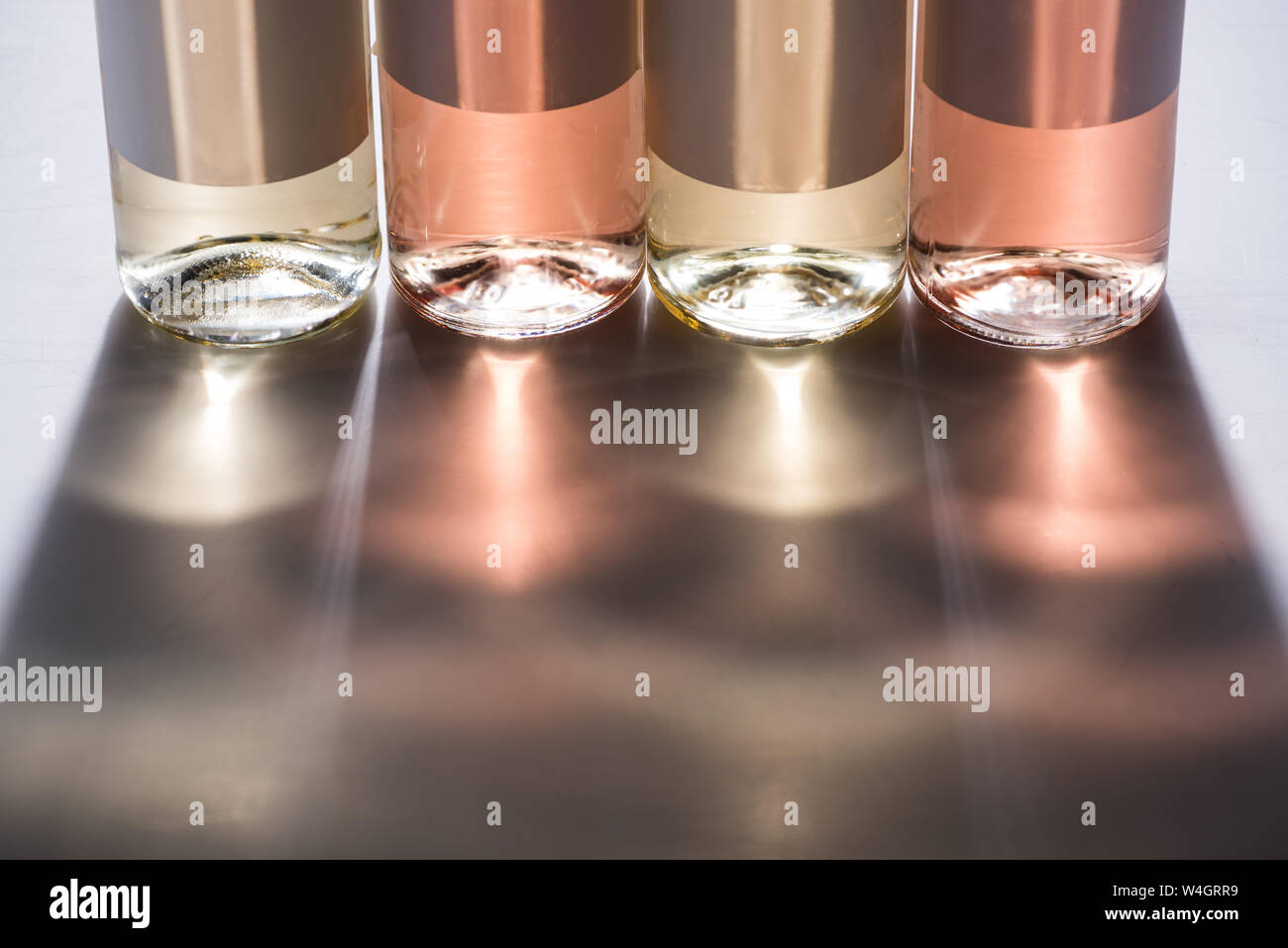 close up view of bottles of white and rose wine with blank labels on ...