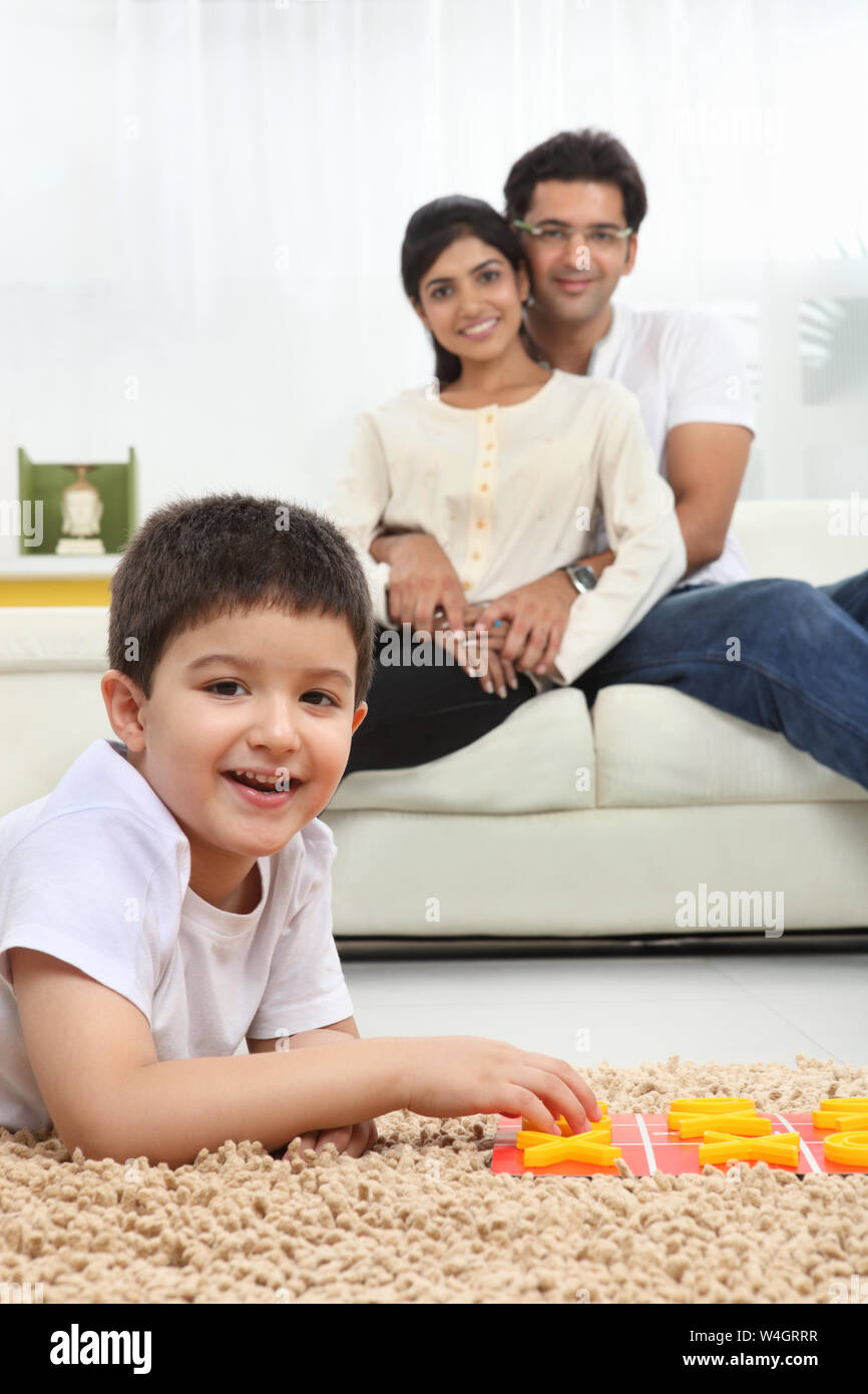 Boy playing tic tac toe with his parents sitting on couch Stock Photo ...