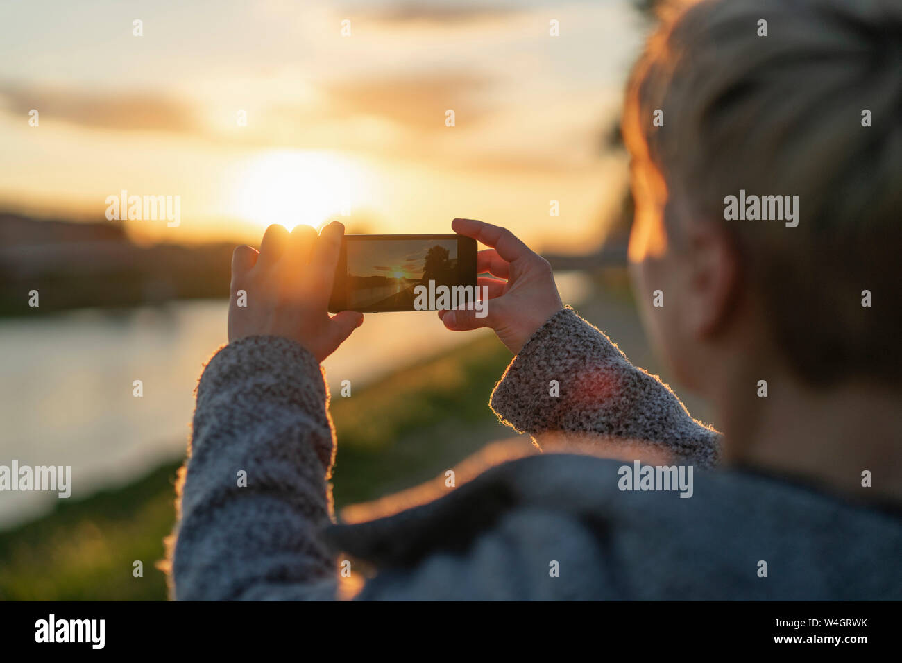 Back view of woman taking photo of sunset, close-up Stock Photo - Alamy
