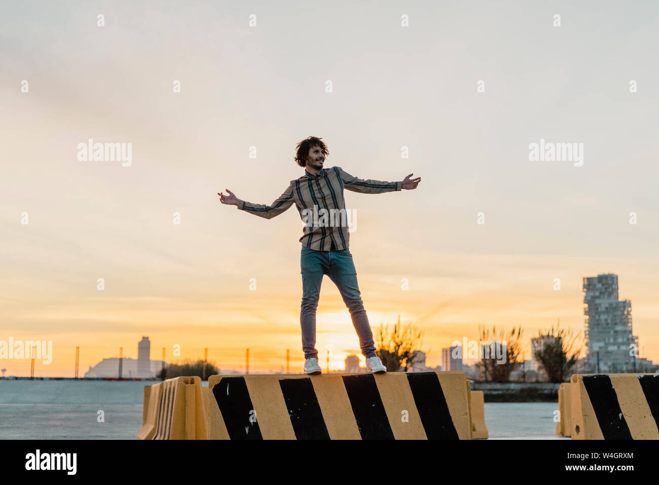 Happy man standing on barrier enjoying sunset hi-res stock photography ...