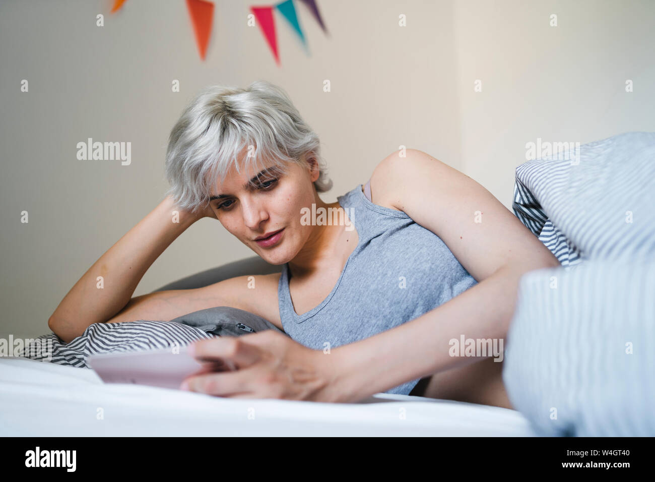 Woman lying in bed using cell phone Stock Photo - Alamy
