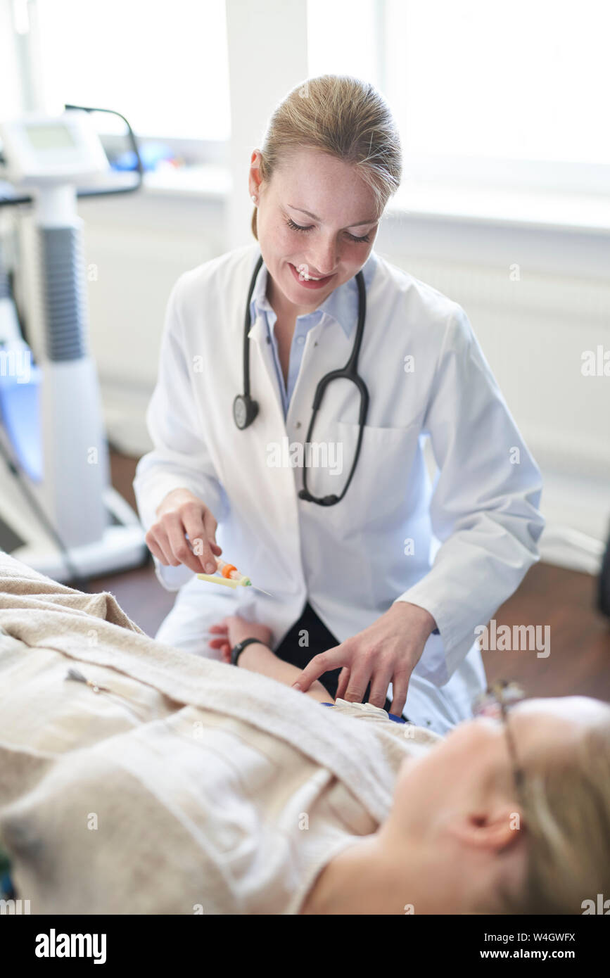 Female doctor taking a blood sample from patient in medical practice ...