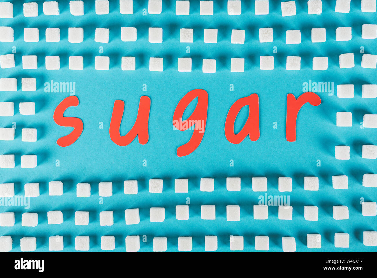 top view of red paper cut word sugar surrounded by white sugar cubes on ...
