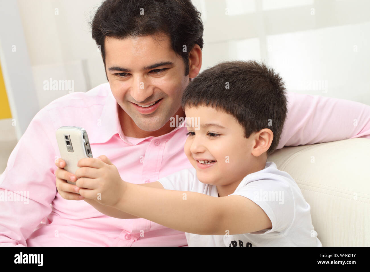 Boy text messaging on a mobile phone with his father Stock Photo - Alamy