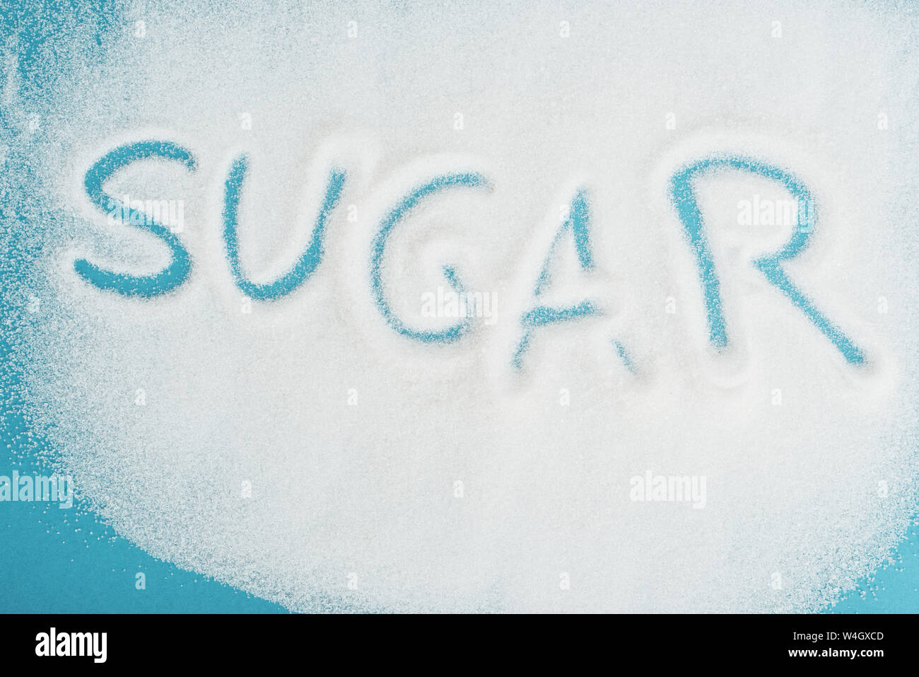 top view of word sugar made on sprinkled white sugar crystals on blue ...