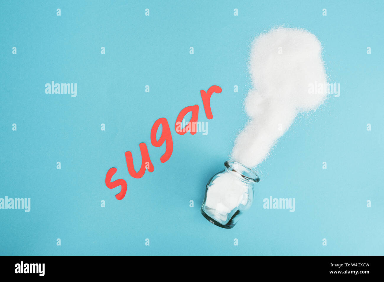 top view of red paper cut word sugar near sugar crystals and glass jar ...