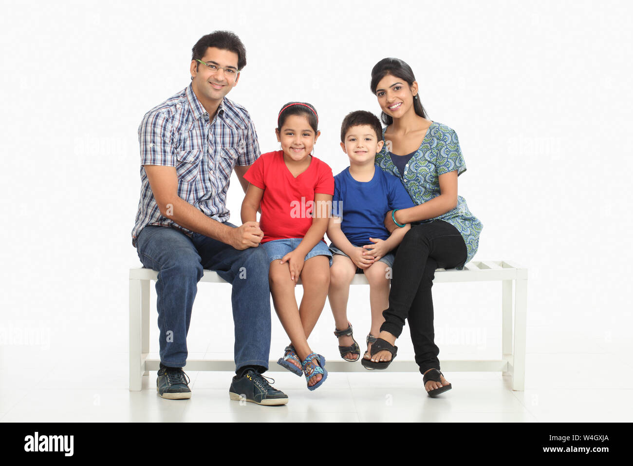 Family sitting on a bench and smiling Stock Photo - Alamy