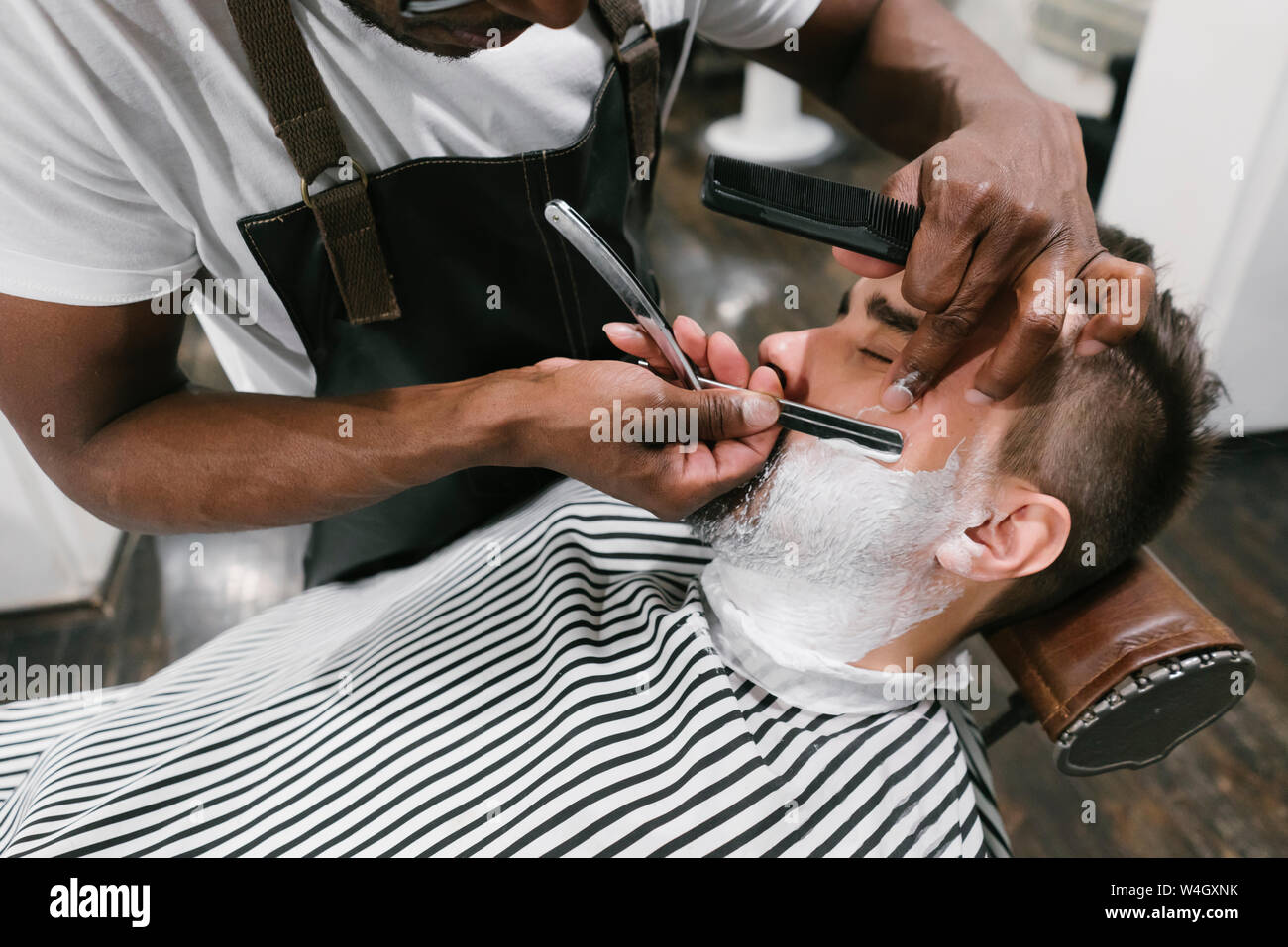 Man getting his beard shaved with razor in barber shop Stock Photo - Alamy