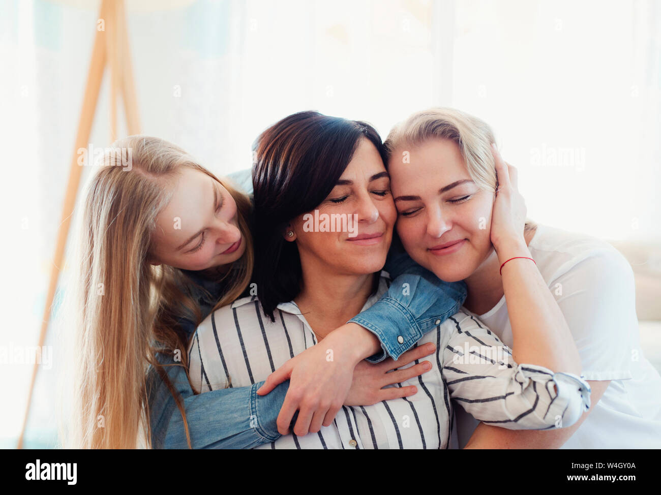 Visiting daughters embracing their mother Stock Photo - Alamy