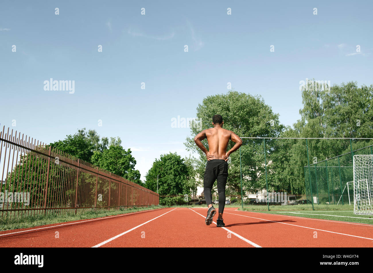 Athletic man walking on rubber racetrack, rear view Stock Photo - Alamy