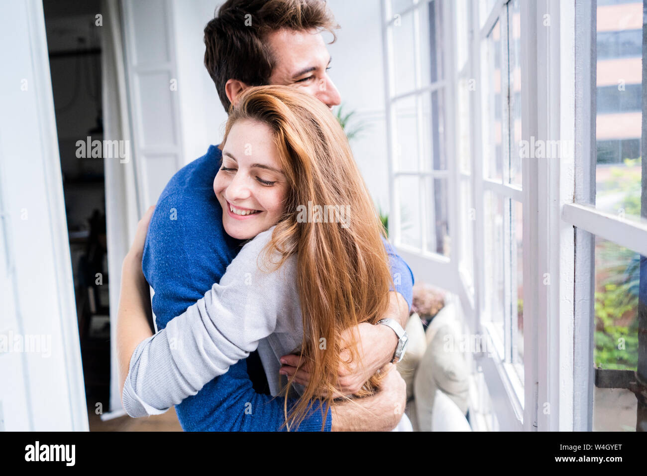 Happy affectionate couple hugging at the window at home Stock Photo - Alamy