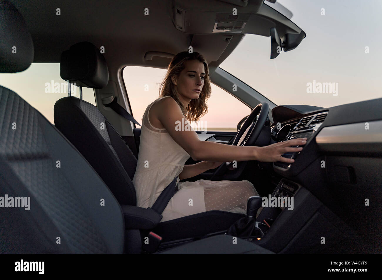 Blond woman driver choosing a radio channel in her car Stock Photo - Alamy