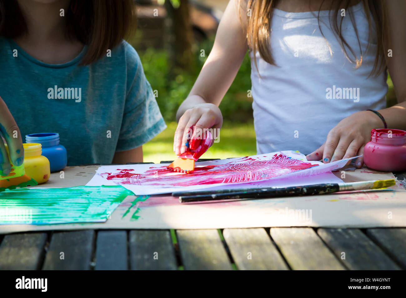 Two girls painting at table in the garden hi-res stock photography and ...