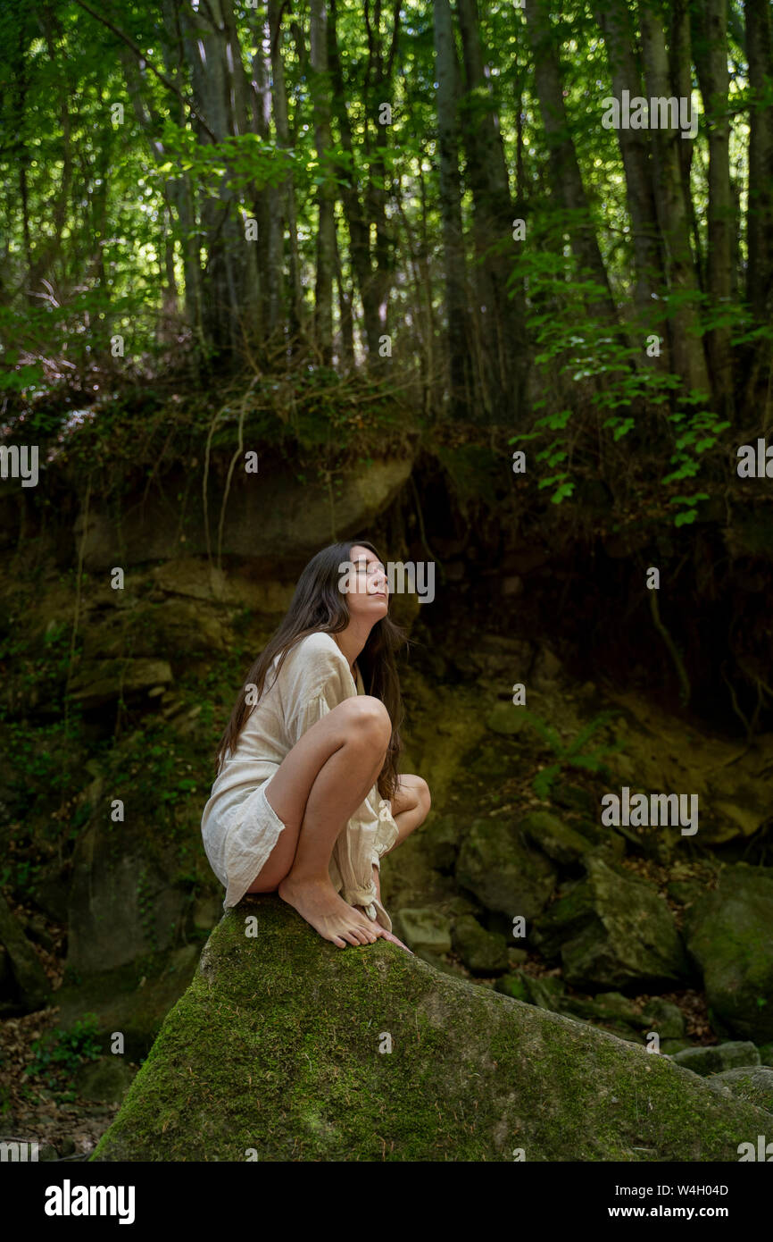 Young woman sitting on a rock in the forest, Garrotxa, Spain Stock ...