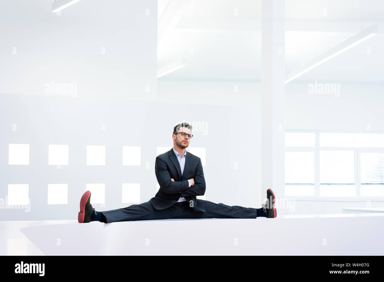 Businessman doing the splits on reception desk in office Stock Photo ...