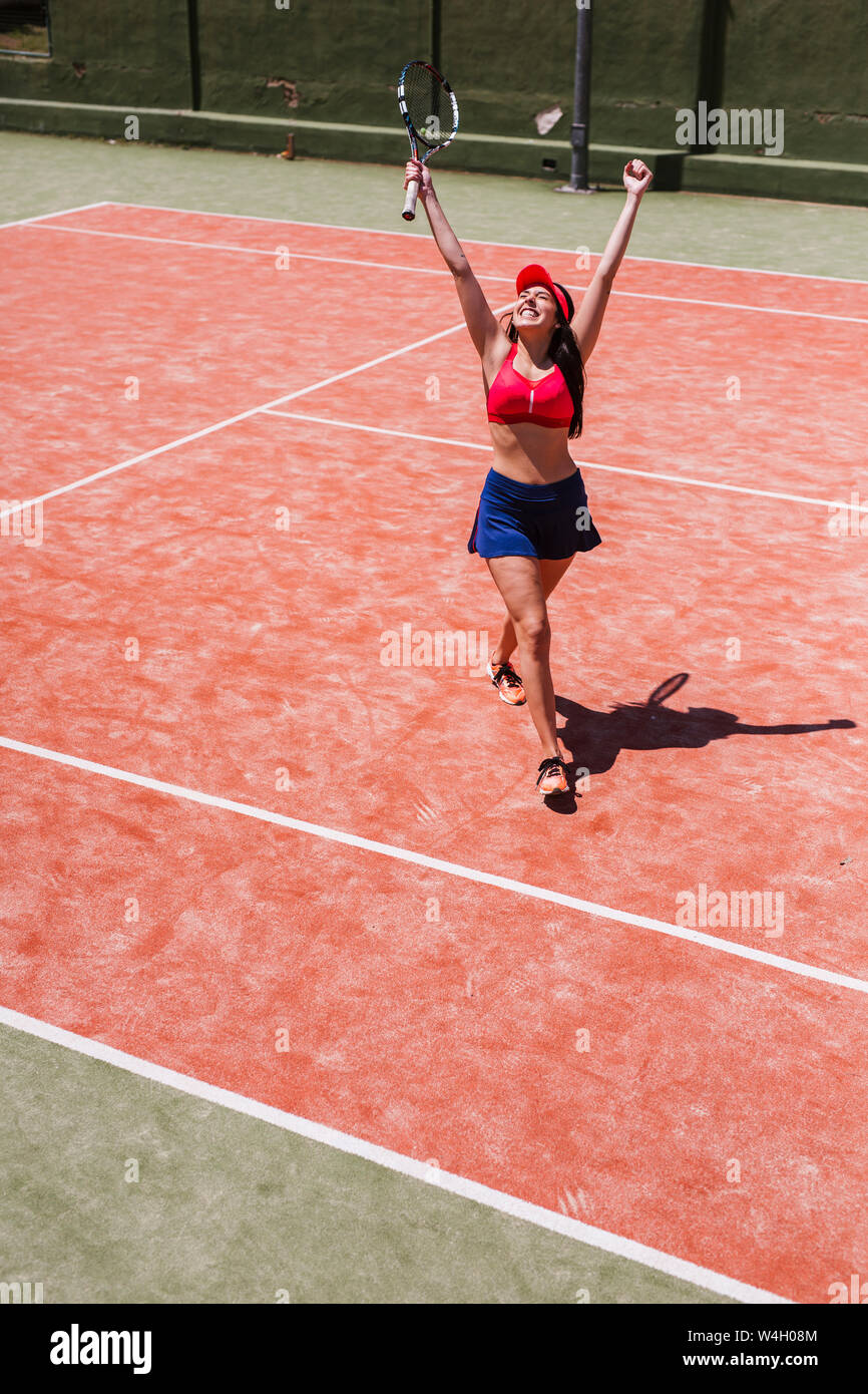 Happy female tennis player cheering on court Stock Photo - Alamy