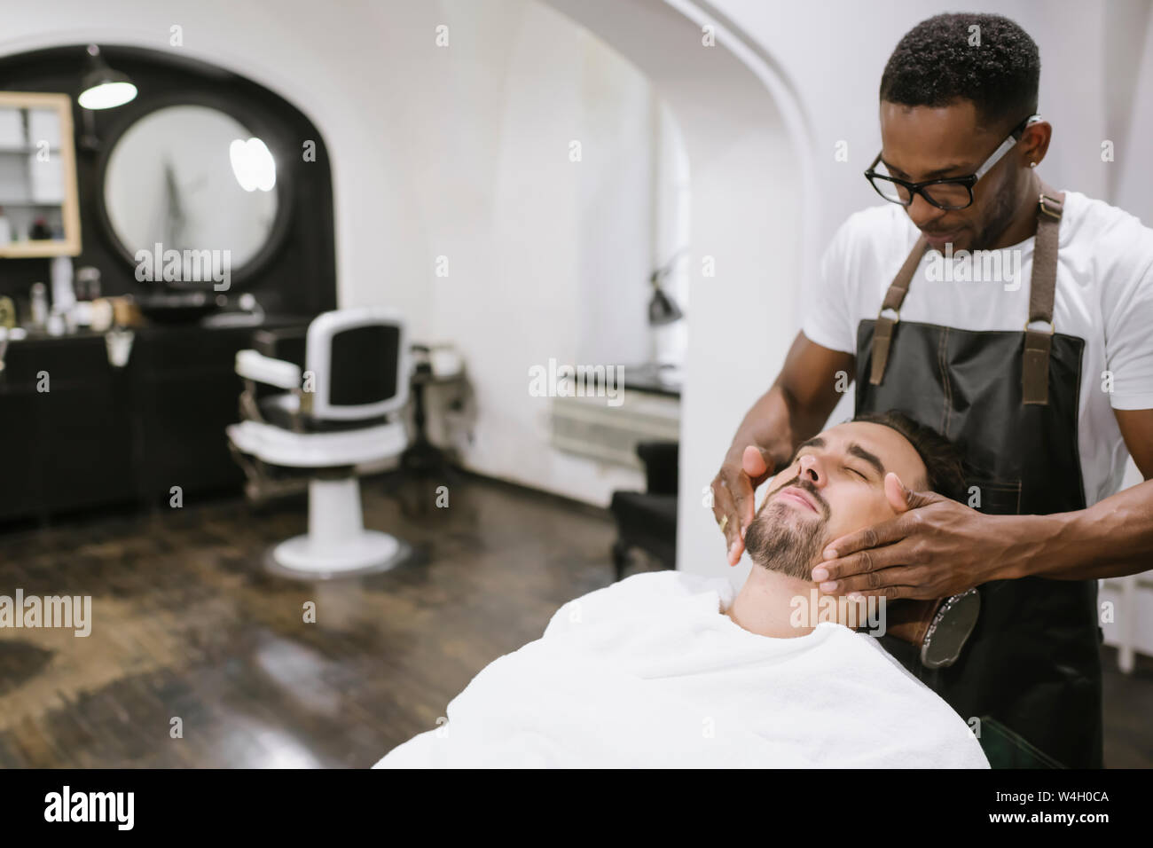 Barber applying after shave to customer's beard in barber shop Stock ...