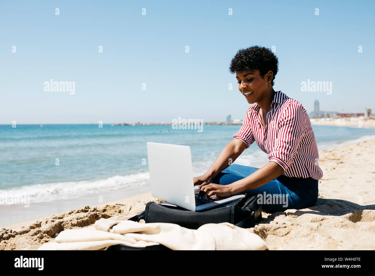 Woman sitting on the beach while working with the laptop Stock Photo ...