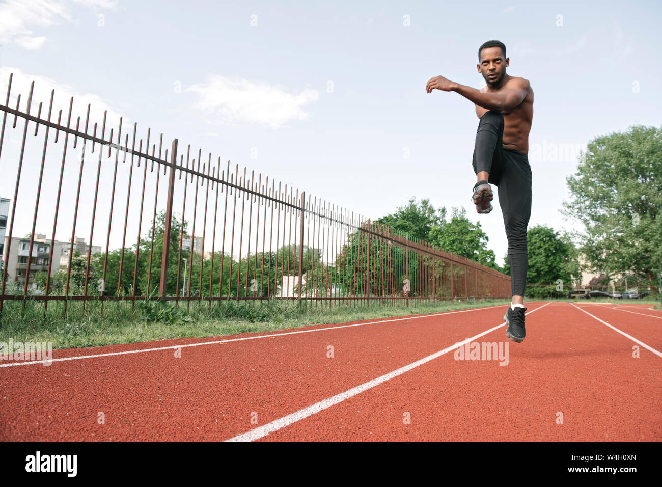 Athletic man caught in mid air while jumping on rubber racetrack Stock ...