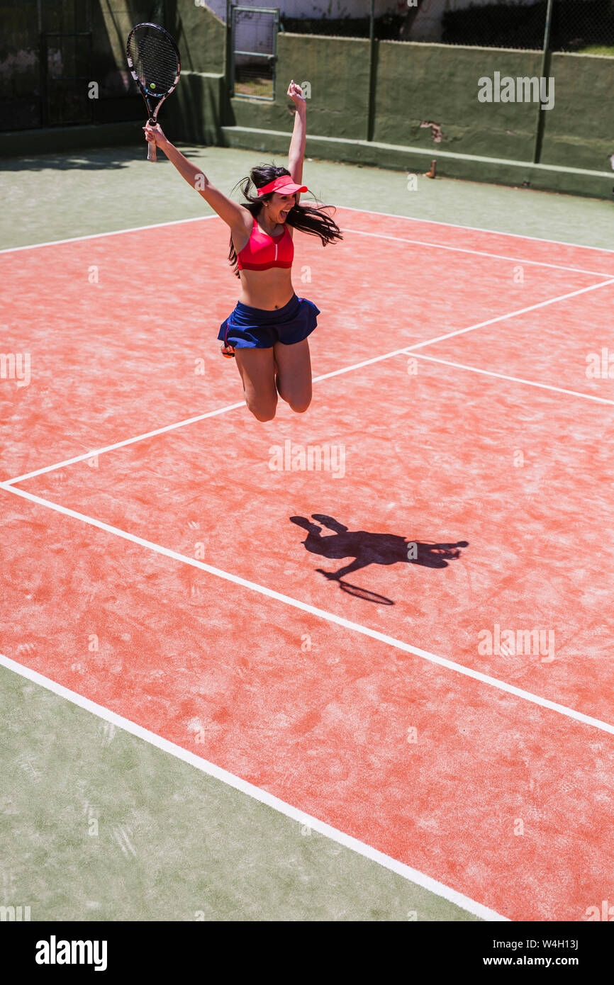 Excited female tennis player cheering on court Stock Photo - Alamy