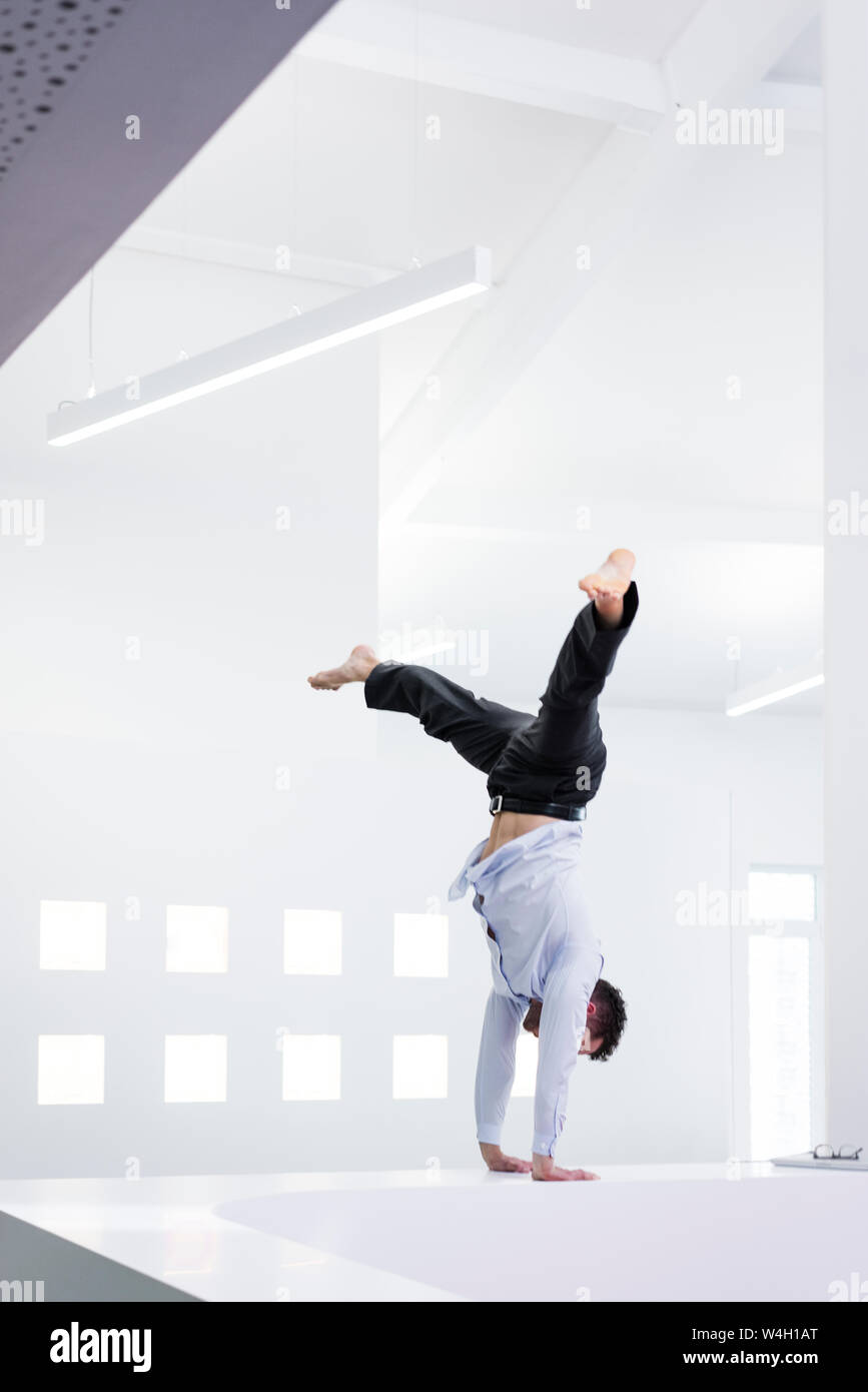 Businessman doing a handstand on reception desk in office Stock Photo ...