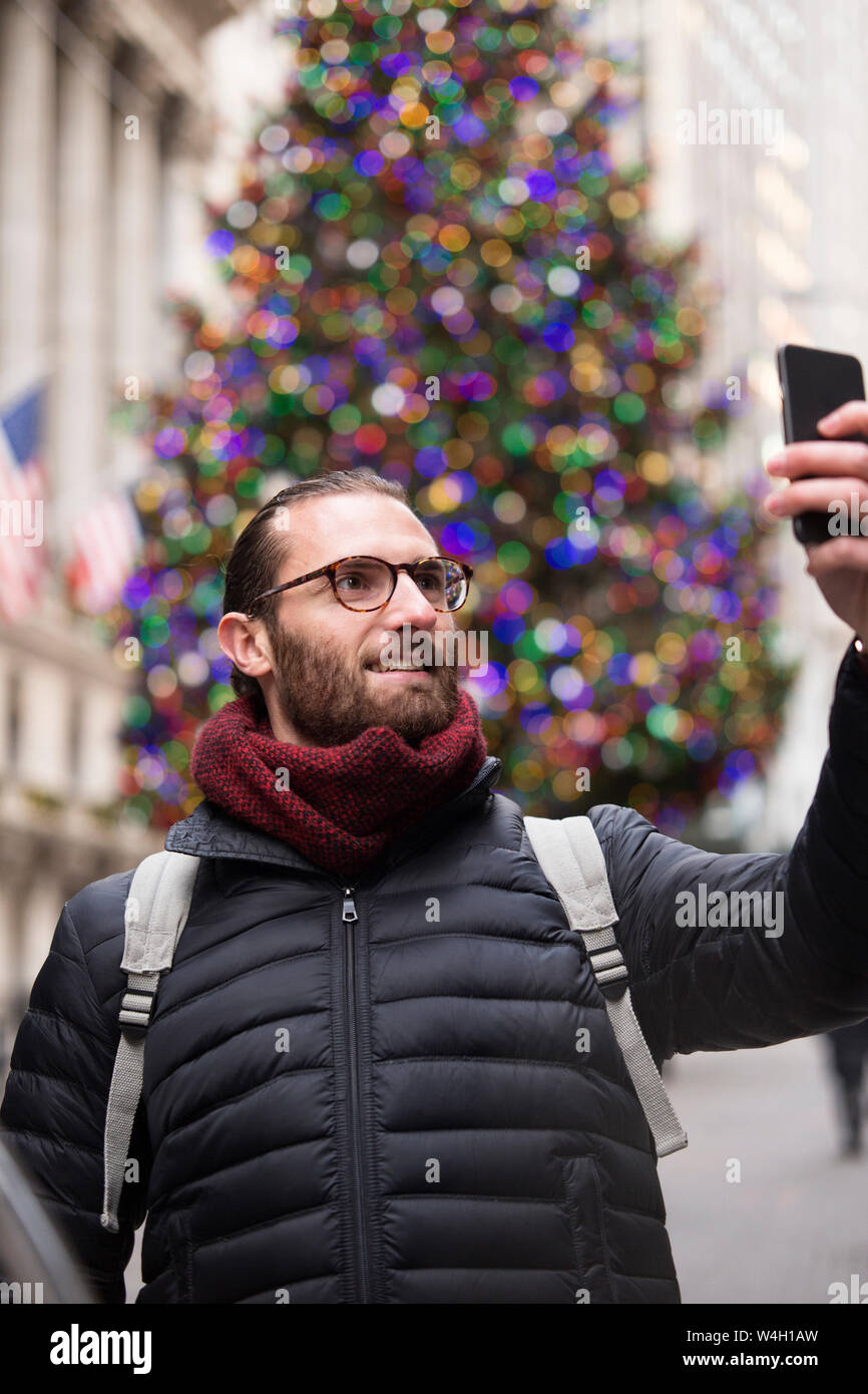 Portrait of tourist taking selfie with smartphone in front of lighted ...