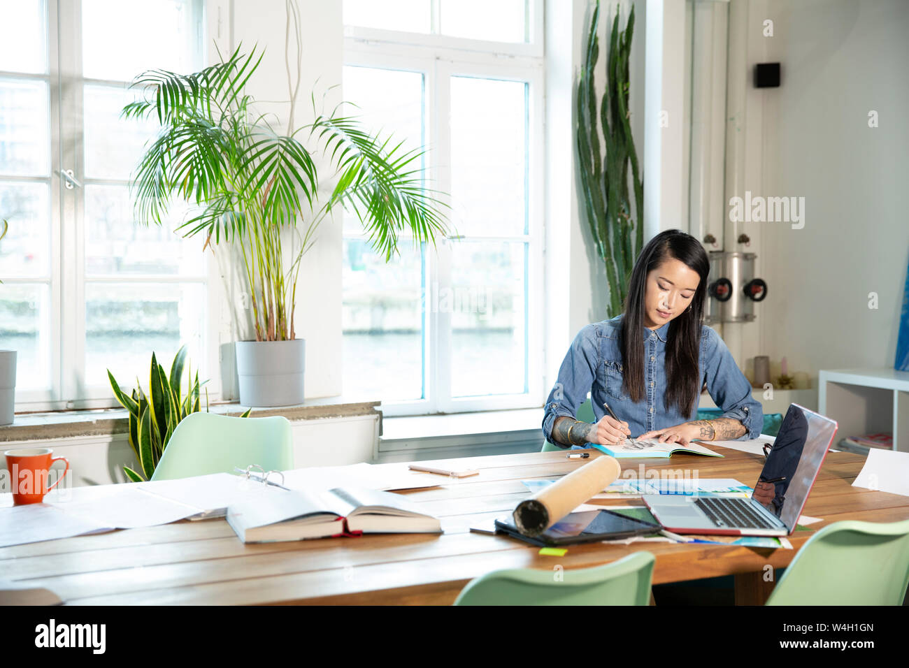 Woman working at table in modern office taking notes Stock Photo - Alamy