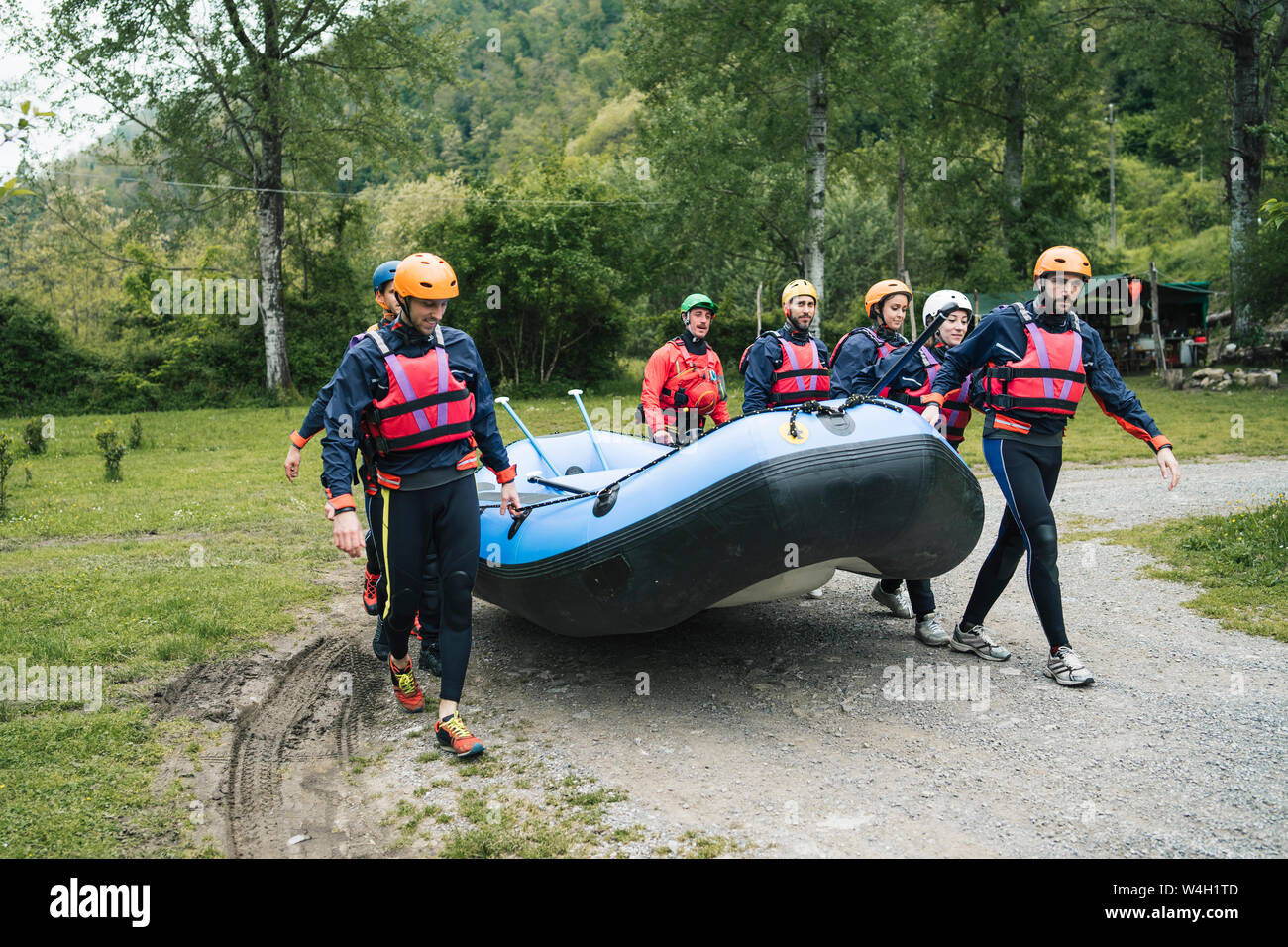 Group of friends preparing for a rafting trip carrying rubber dinghy ...