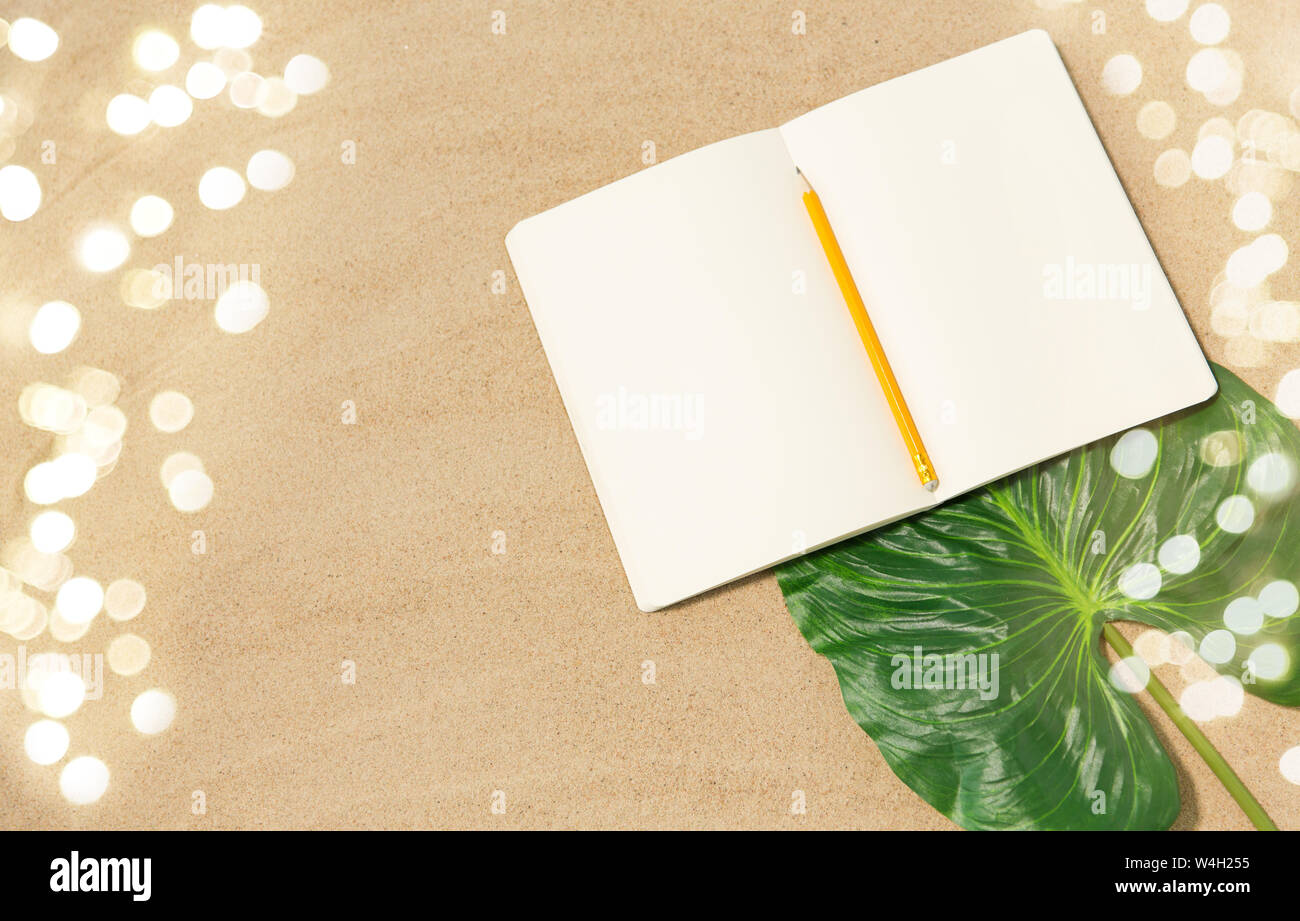 notebook with pencil and leaf on beach sand Stock Photo - Alamy