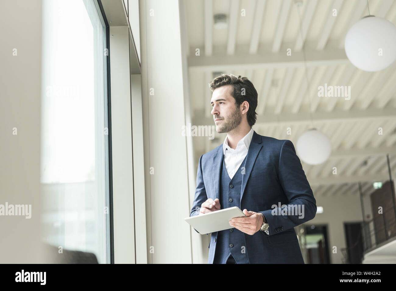 Successful manager standing in modern office building, using laptop ...