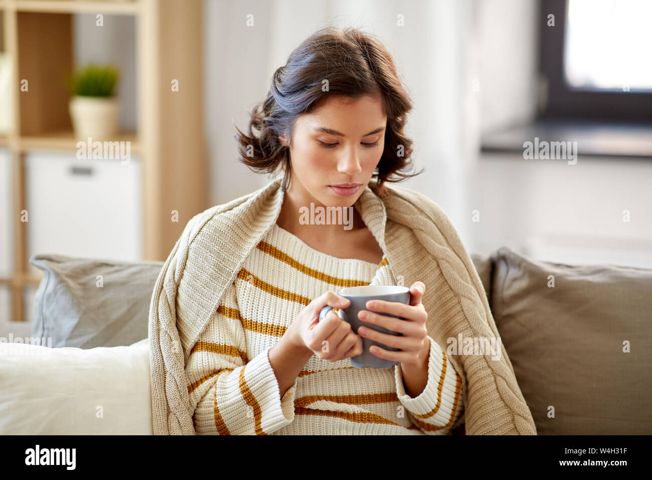 sad sick young woman drinking hot tea at home Stock Photo - Alamy