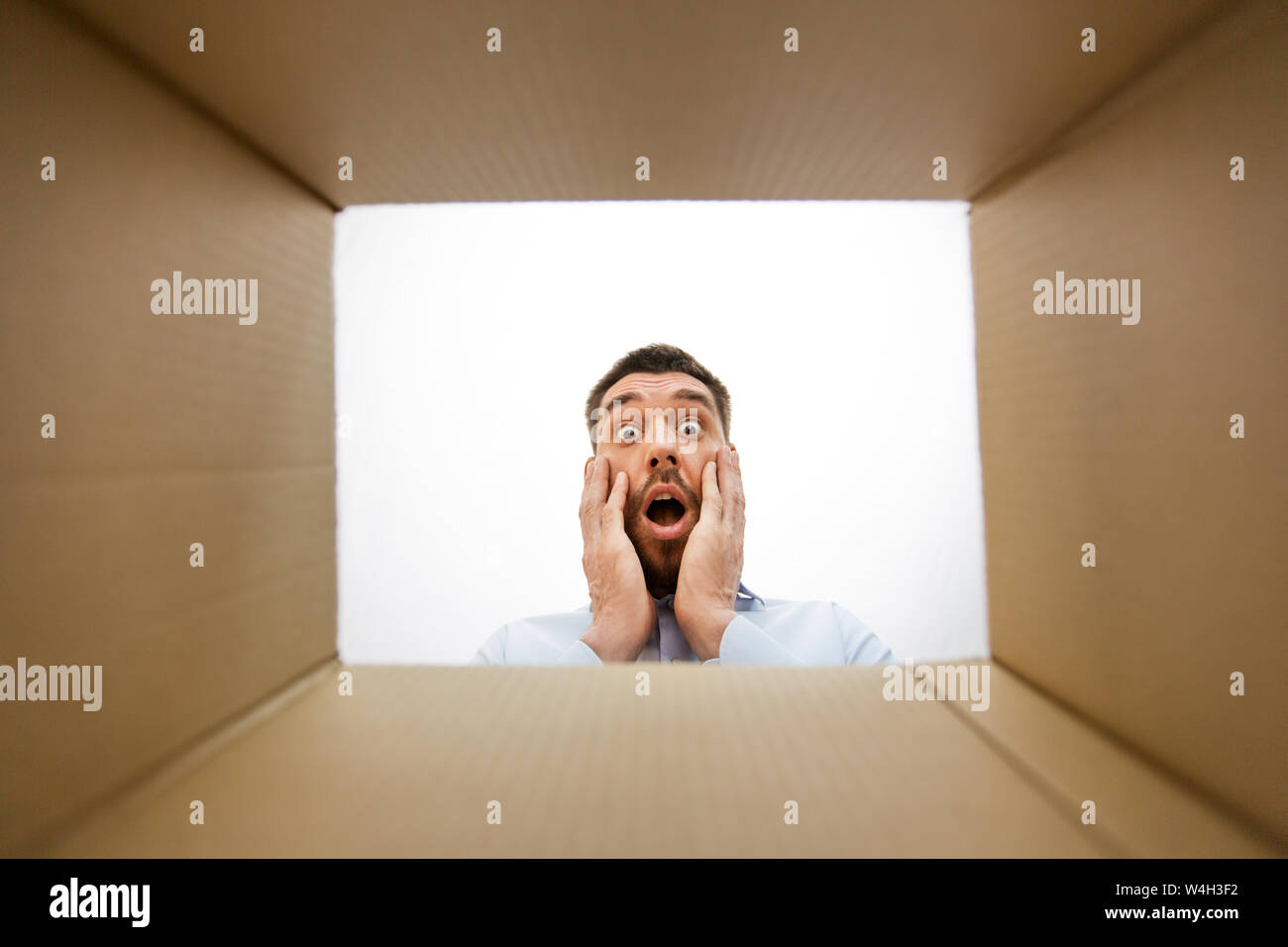 shocked man looking into open parcel box Stock Photo - Alamy