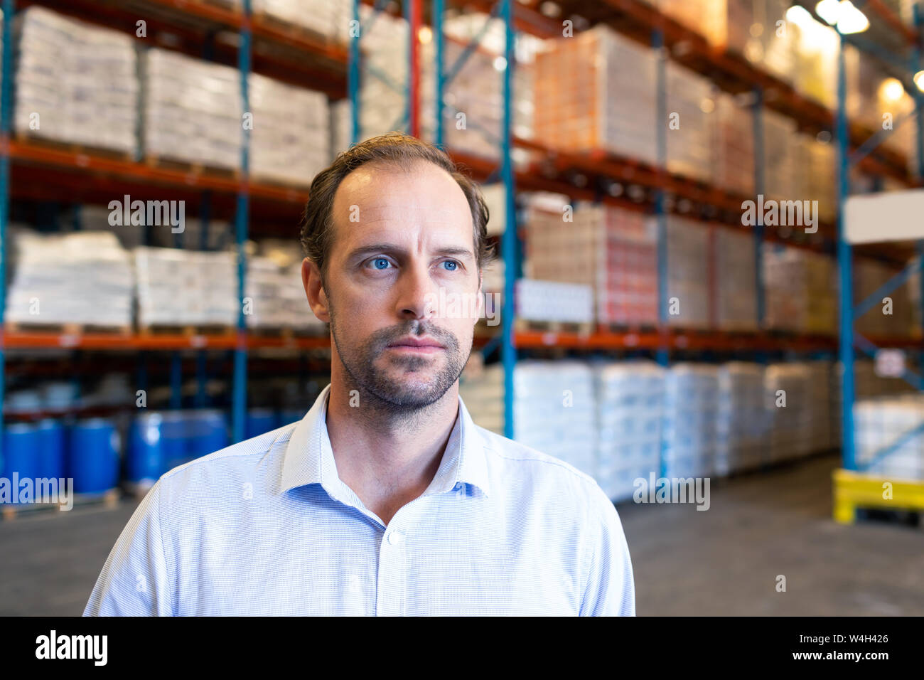 Male supervisor looking away in warehouse Stock Photo - Alamy