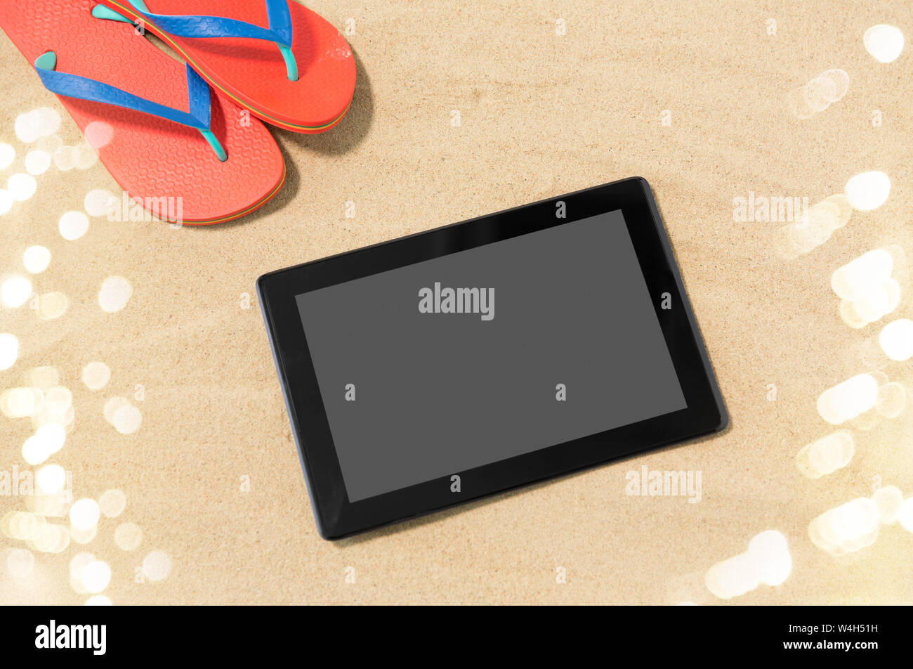 tablet computer and flip flops on beach sand Stock Photo - Alamy