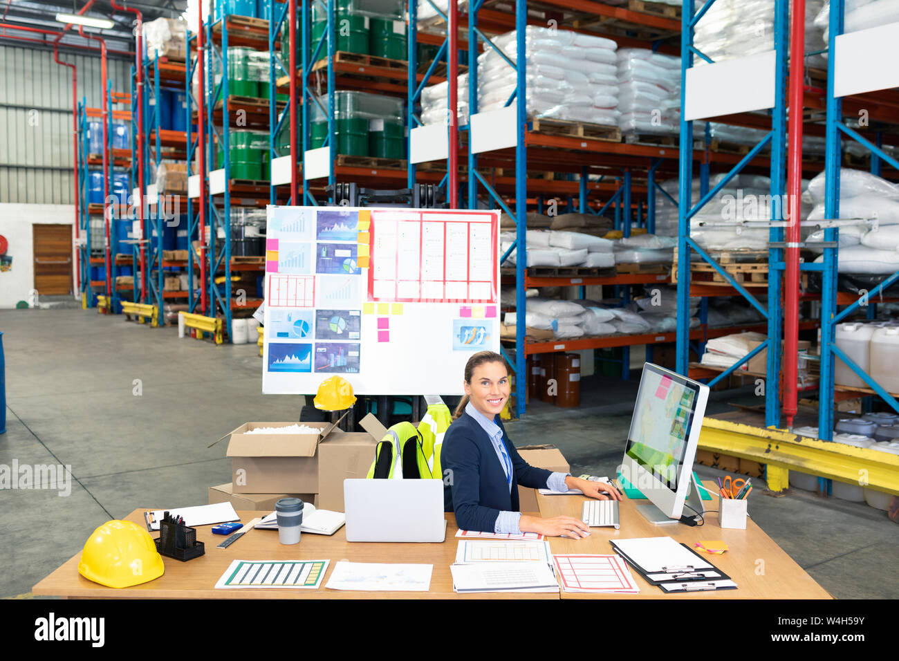 Female manager working on computer at desk in warehouse Stock Photo - Alamy