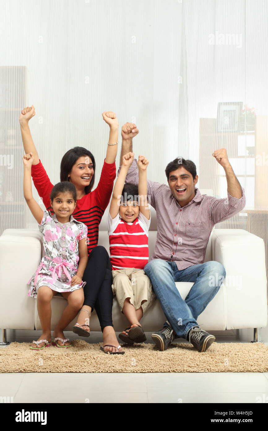 Family sitting on a couch looking excited Stock Photo - Alamy